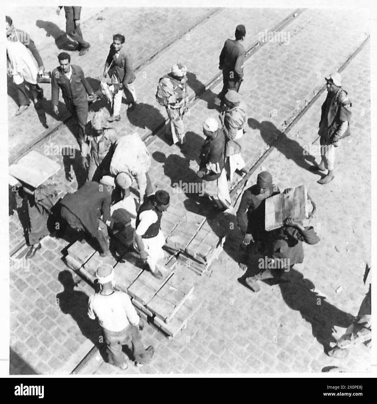 THE M.E.F. MANUFACTURERS ITS OWN PETROL TINS - Further views of stevedores manhandling the metal ...