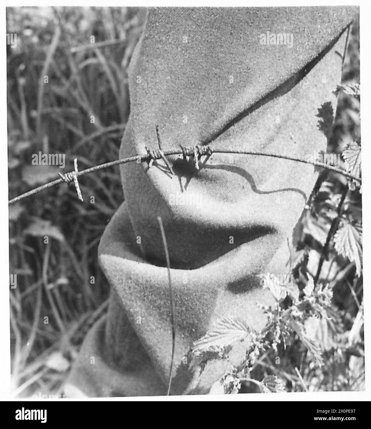 A soldier's battle dress trousers are shown caught in barbed wire ...