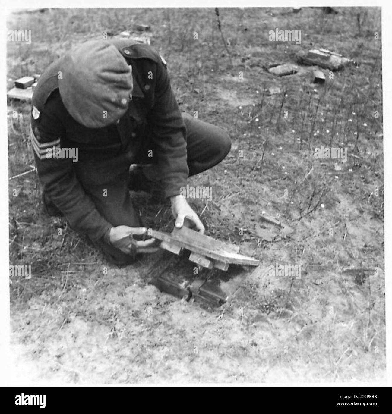 An R.E. Sergeant inspects a box mine at an airfield under preparation ...