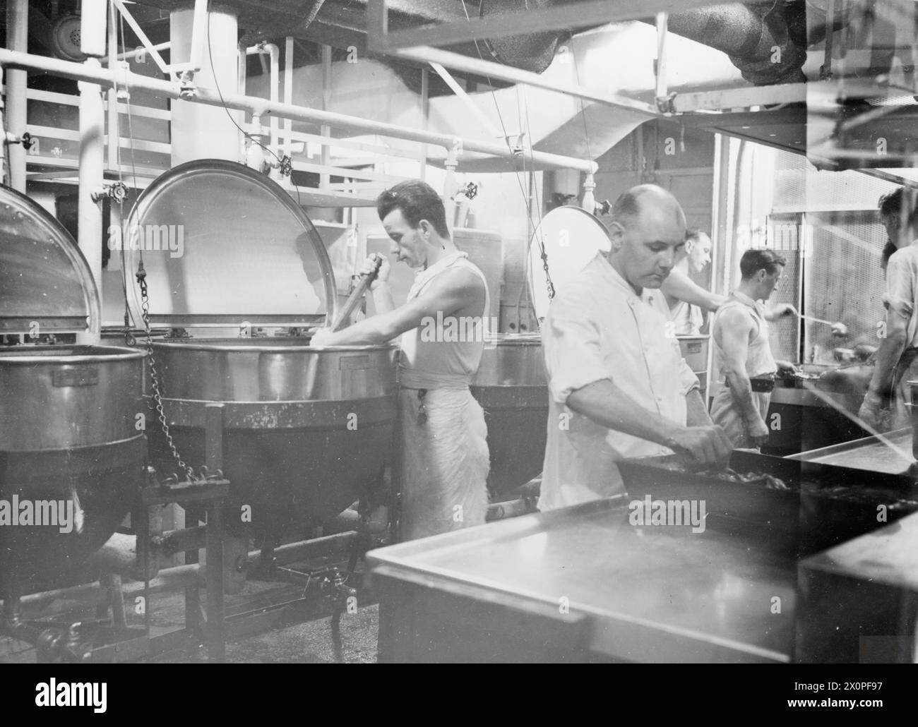Crew prepare dinner in the galley aboard the escort carrier HMS Battler ...