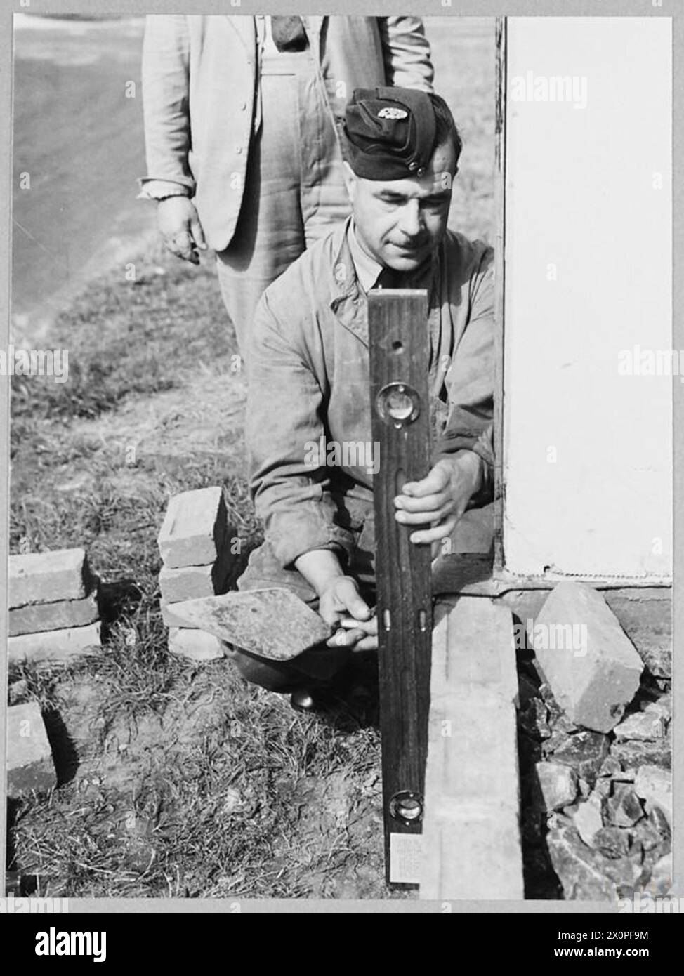Leading Aircraftman H.J. Clark practices bricklaying using a level to ...