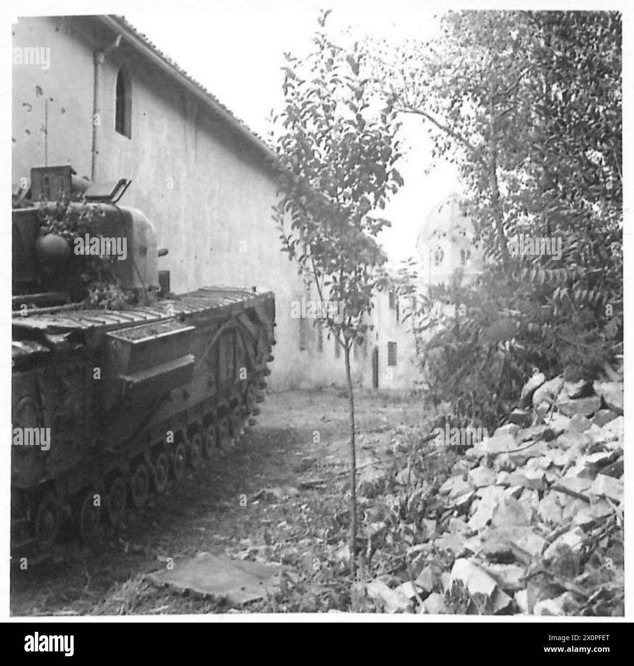 A Churchill 75 mm tank of the North Irish Horse guards a track leading ...