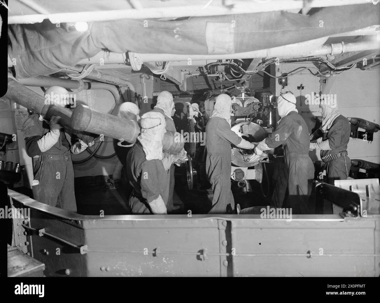 Crew operate a 6-inch gun on HMS Malaya wearing anti-flash gear ...
