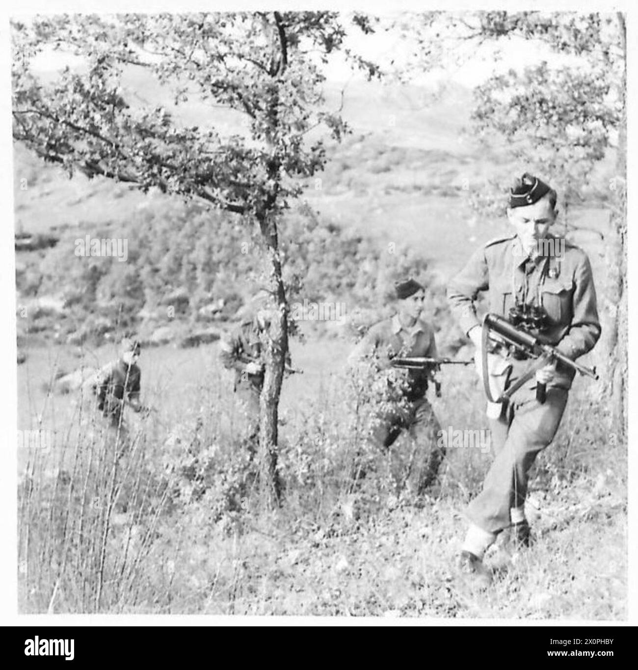 Photograph showing a patrol moving up a hillside in Italy with carrier ...
