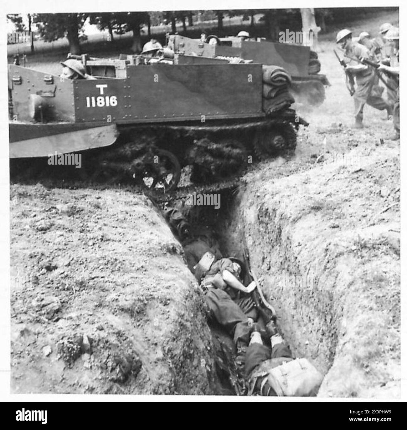 A Bren carrier crosses a trench in Northern Ireland while troops lie in ...