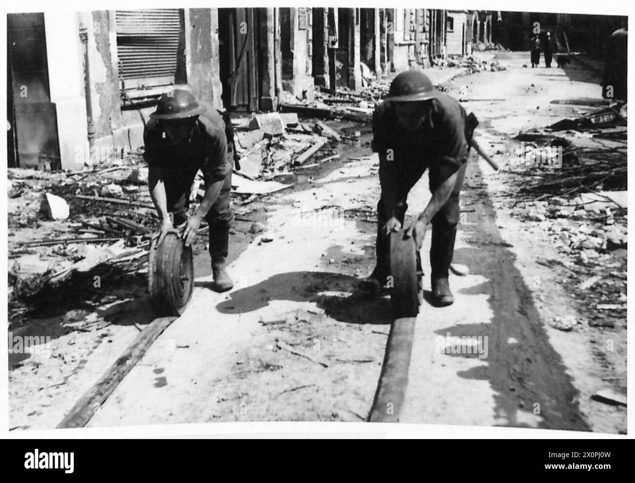 THE ARMY FIRE SERVICE - The fire out two of the team roll up the hoses ...