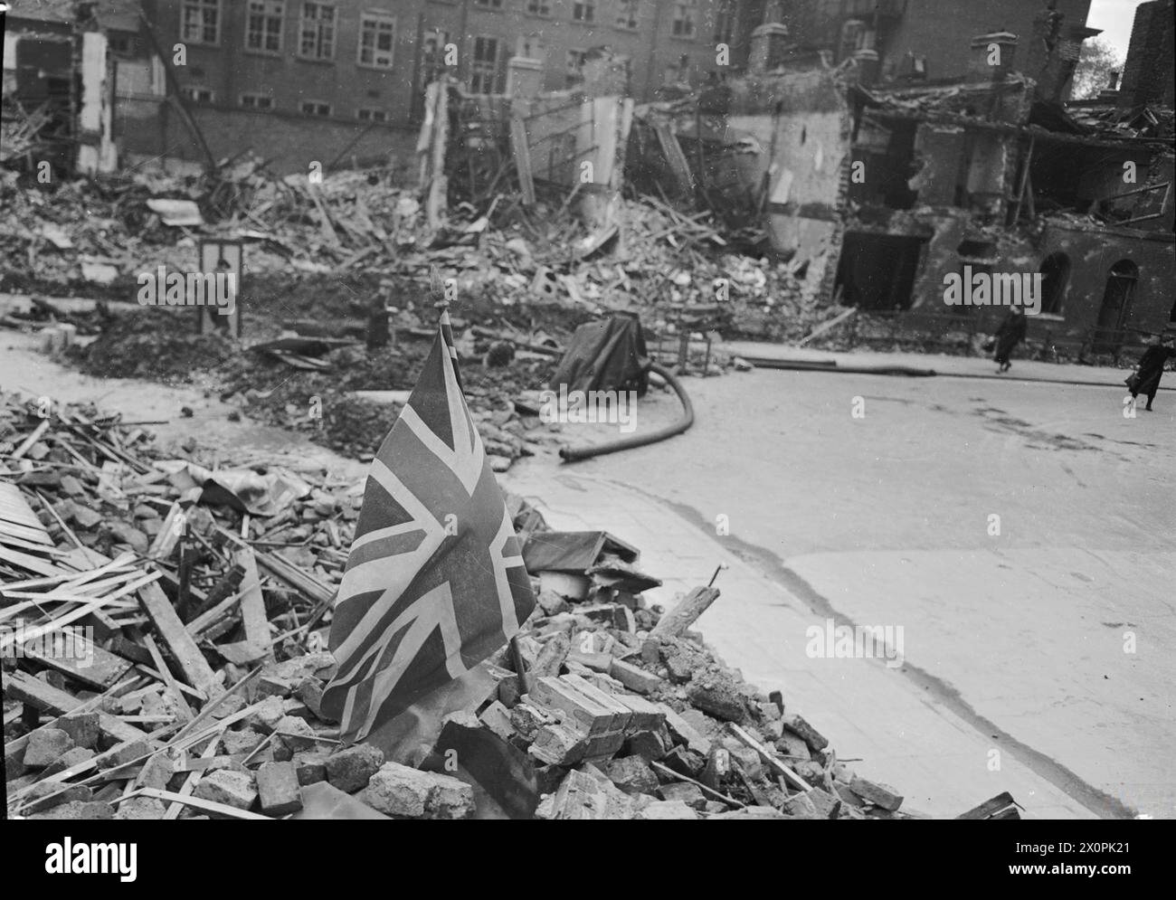 In 1940, a Union Flag stands amidst rubble on a bomb-damaged street in ...