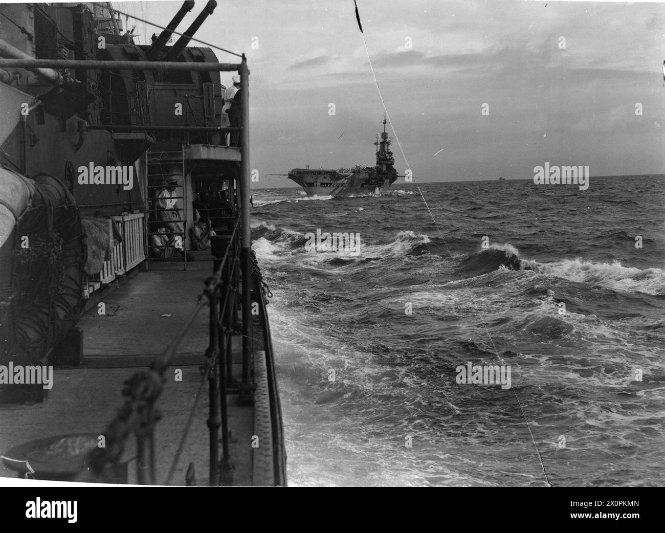 HMS Illustrious, an aircraft carrier, is seen from HMS Mauritius, a ...