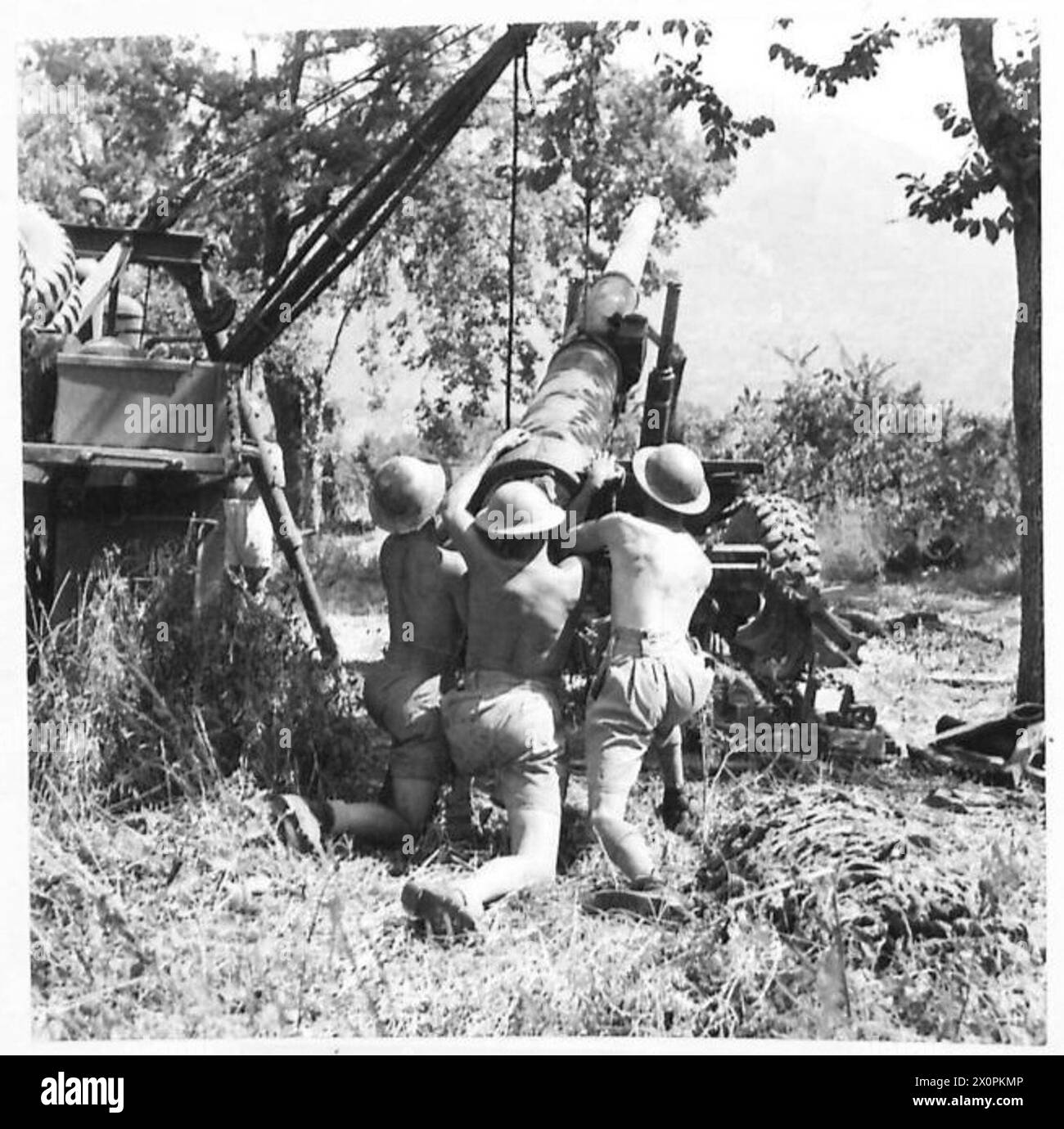 Soldiers perform maintenance on a medium gun in the field, welding and ...