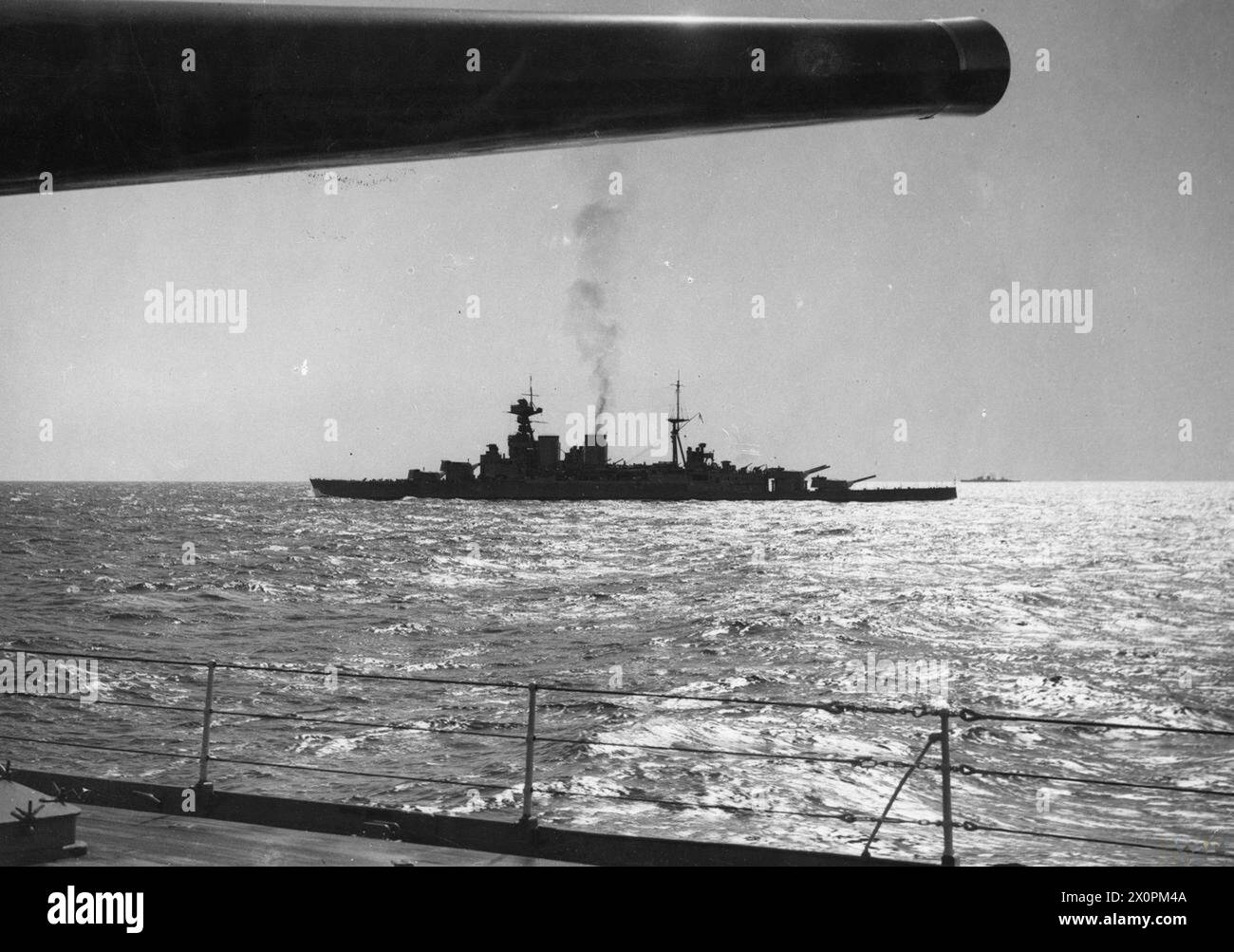 HMS Hood is pictured at a distance under the 15-inch gun of HMS Renown ...