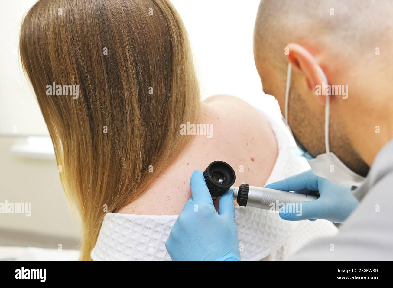 dermatologist examines neoplasms on the patient's skin using a special ...