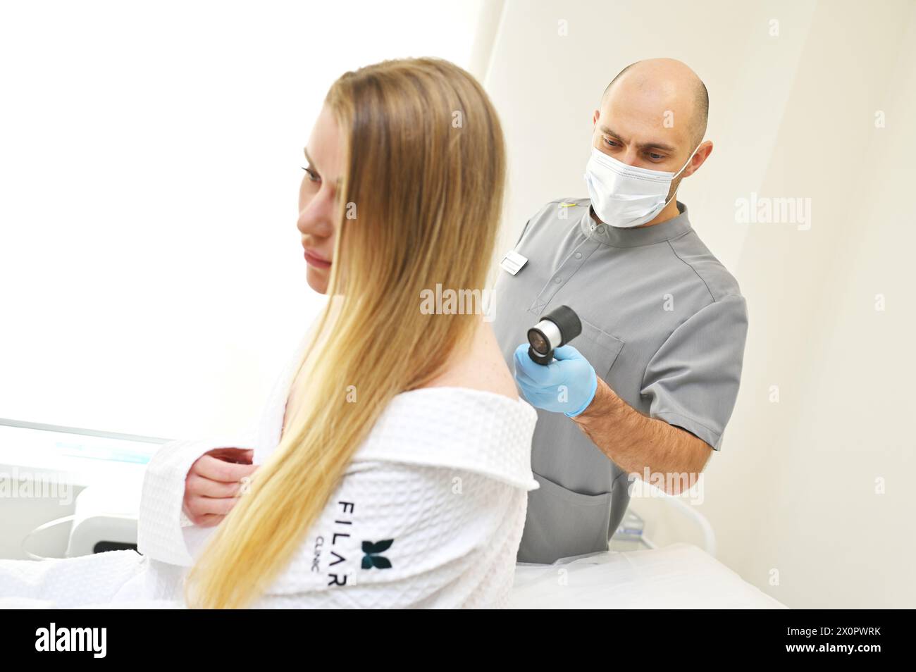 dermatologist examines neoplasms on the patient's skin using a special ...
