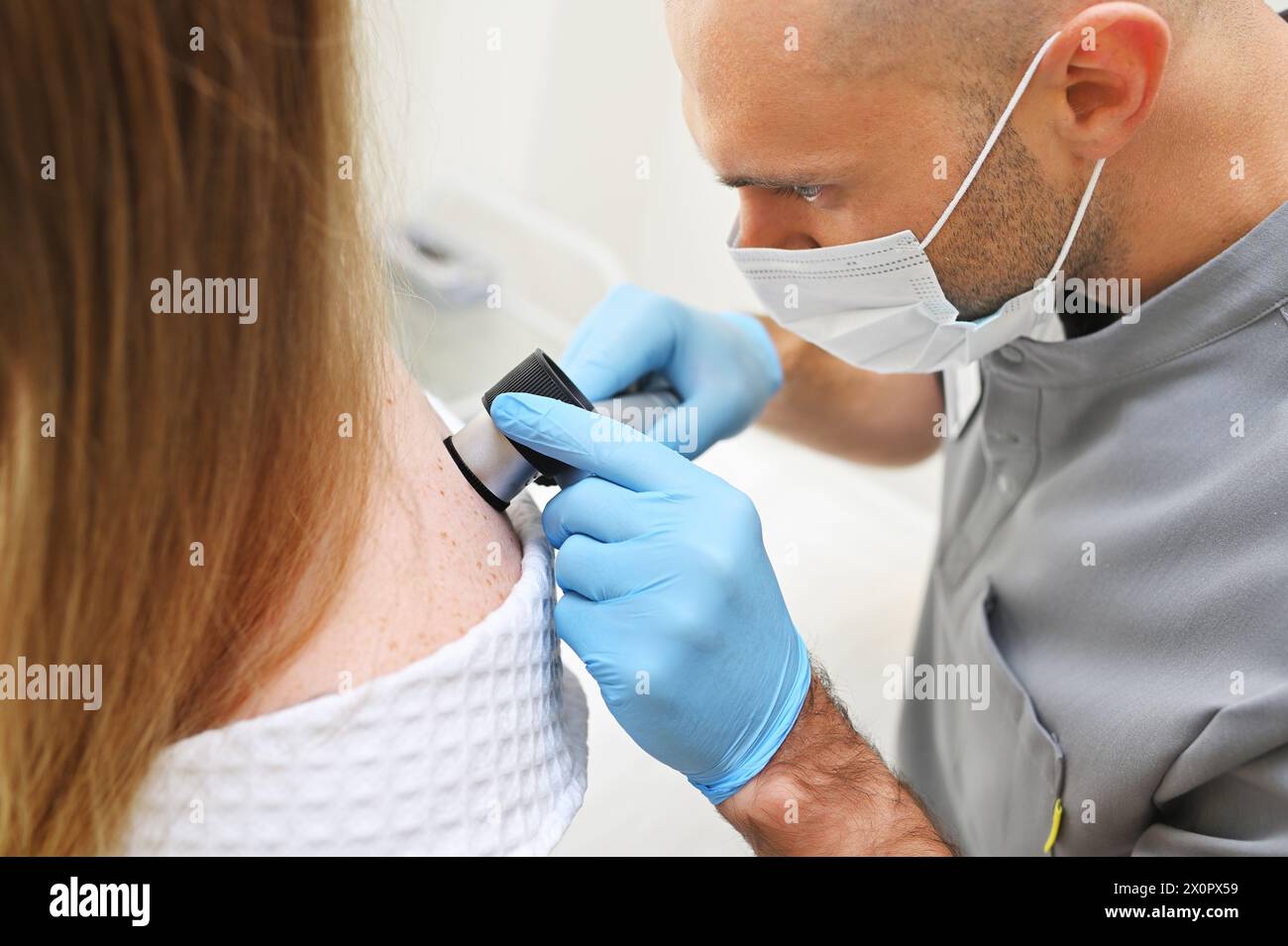 dermatologist examines neoplasms on the patient's skin using a special ...