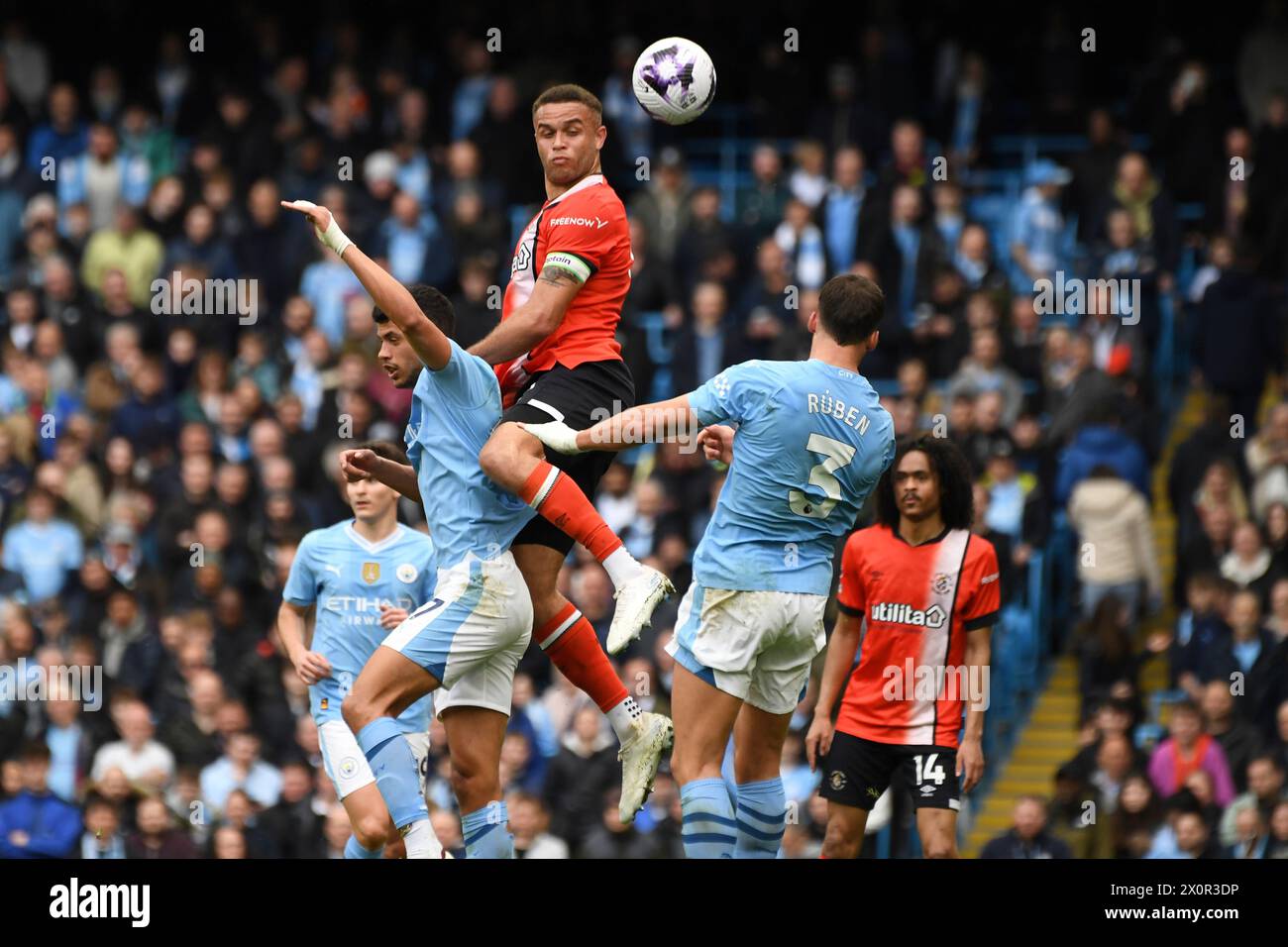 Luton Town's Carlton Morris, centre, heads the ball ahead of Manchester ...