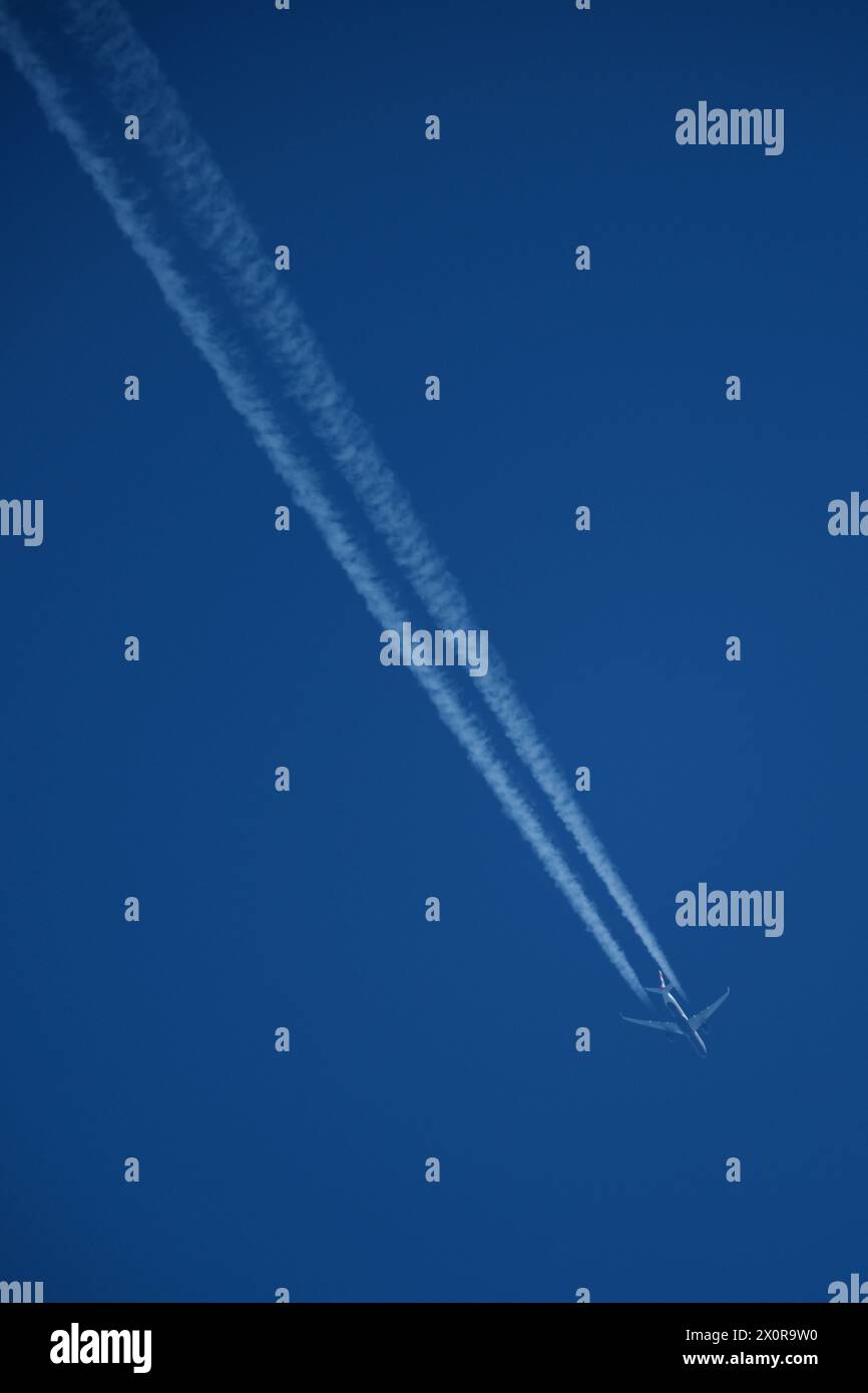 Airplane in the blue sky with contrail Stock Photo - Alamy