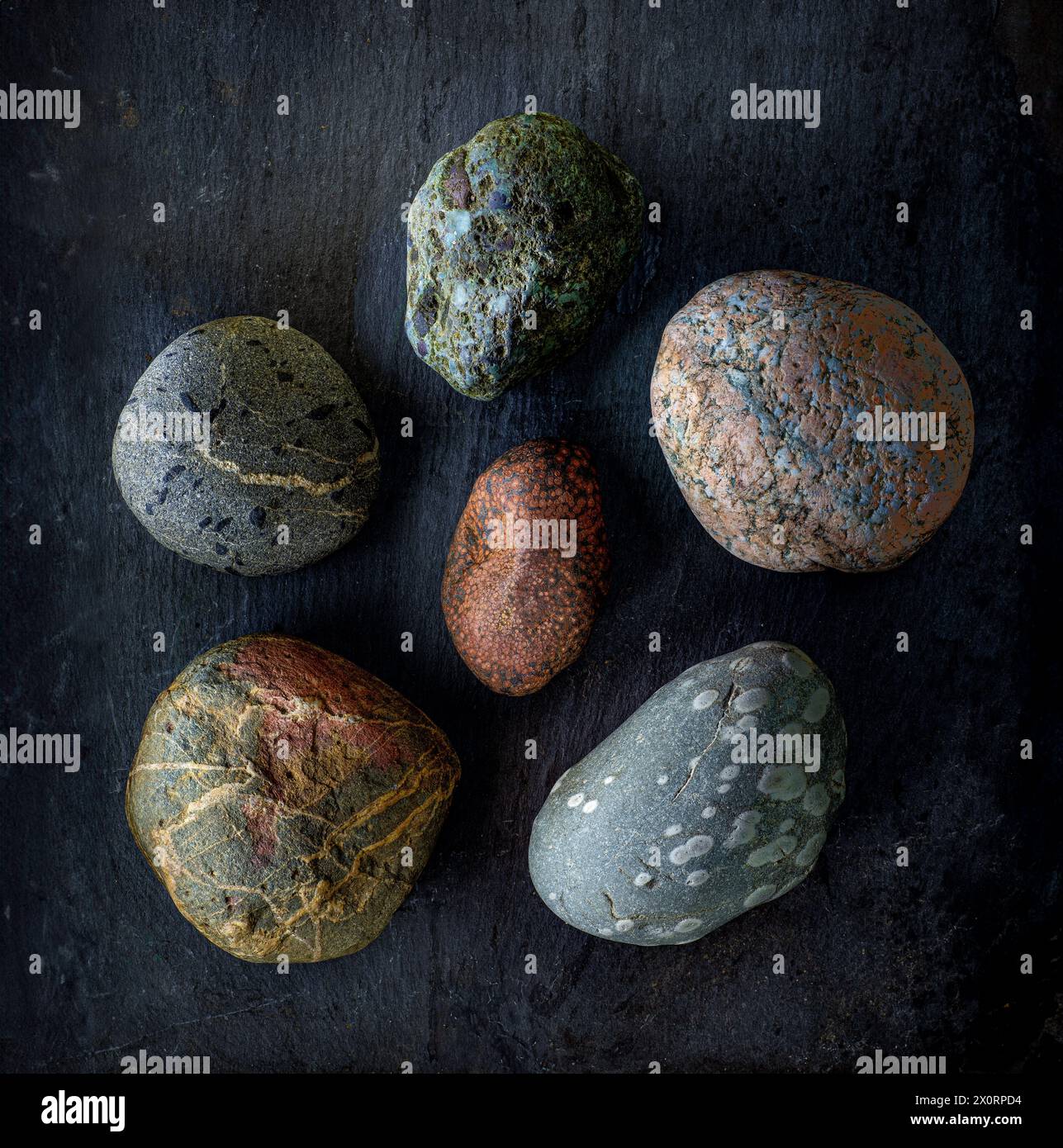 Six rocks on slate surface and light-painted from the side Stock Photo ...
