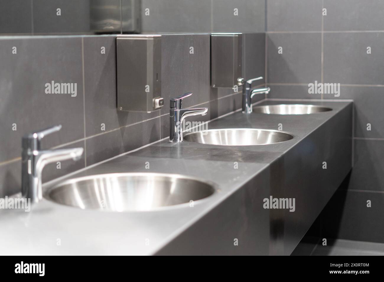 A row of metallic toilets in a gray tiled public toilet Stock Photo - Alamy