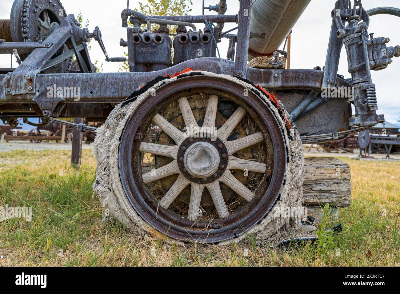 A ruined tire is falling off a wheel with wooden spokes and a metal rim ...