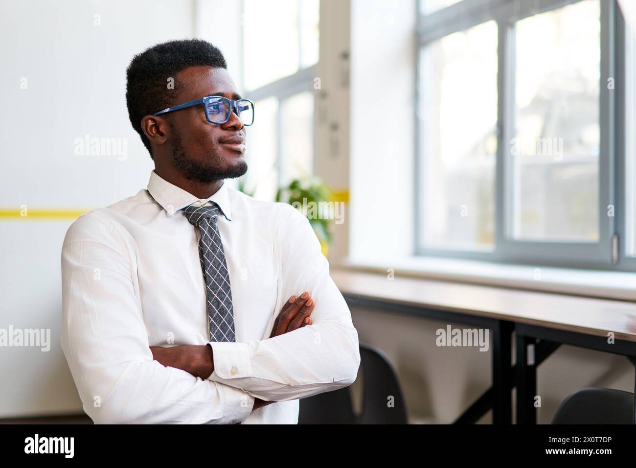 Confident African corporate pro stands in modern office, arms crossed ...