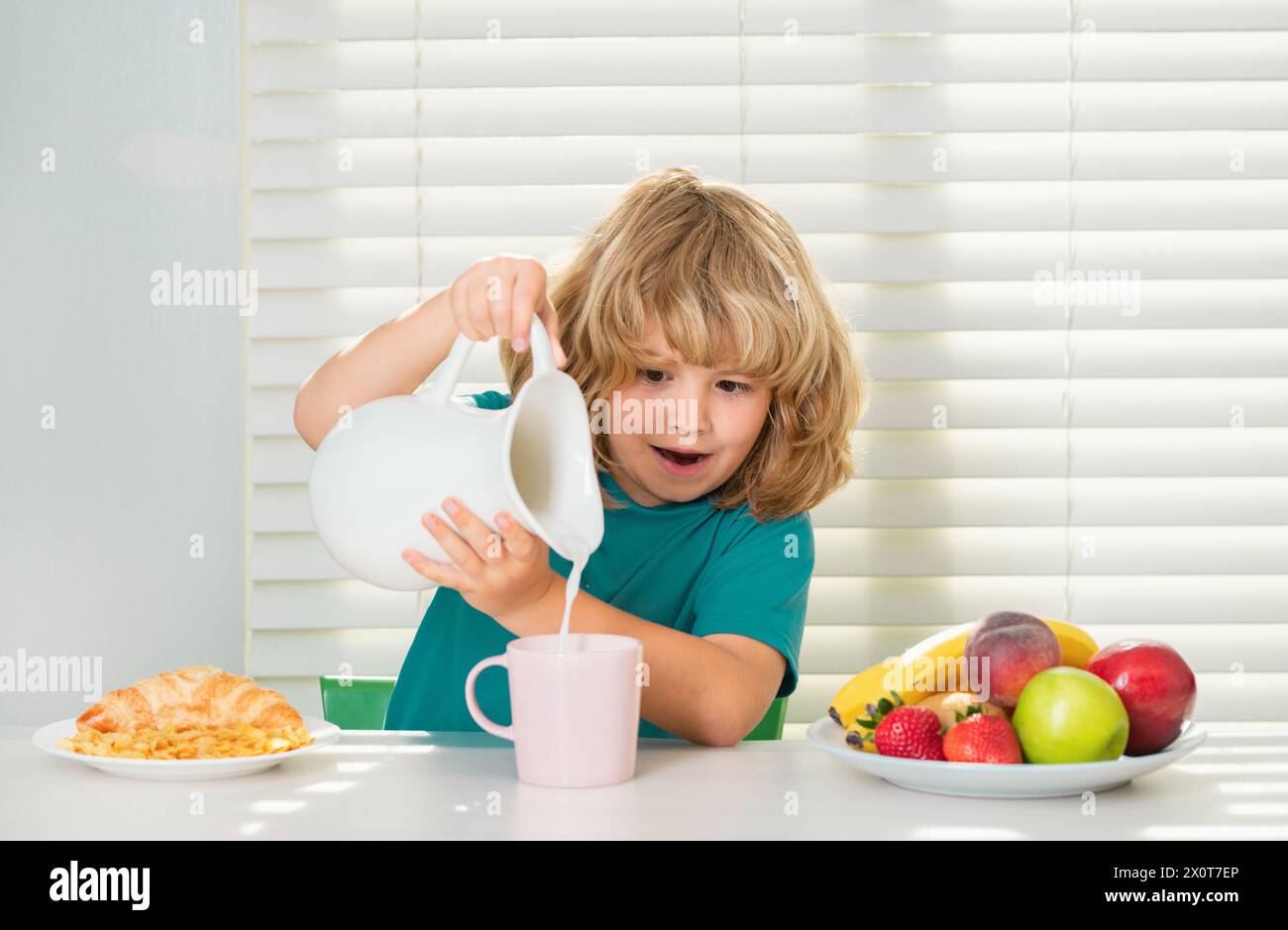 Kid pouring whole cows milk. Kid preteen boy in the kitchen at the ...