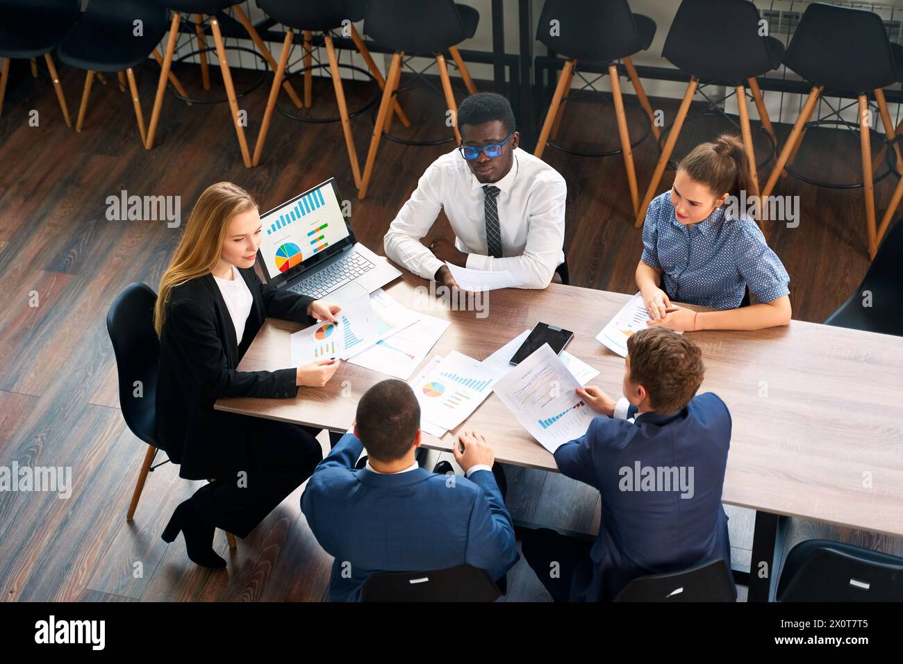 Female CEO leads business meeting, analyzes charts on laptop in modern ...
