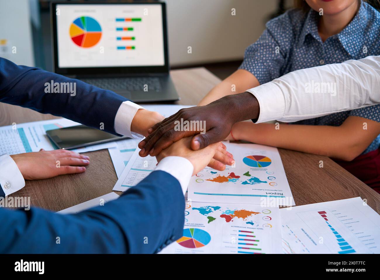 Multiracial hands come together over business charts in office ...