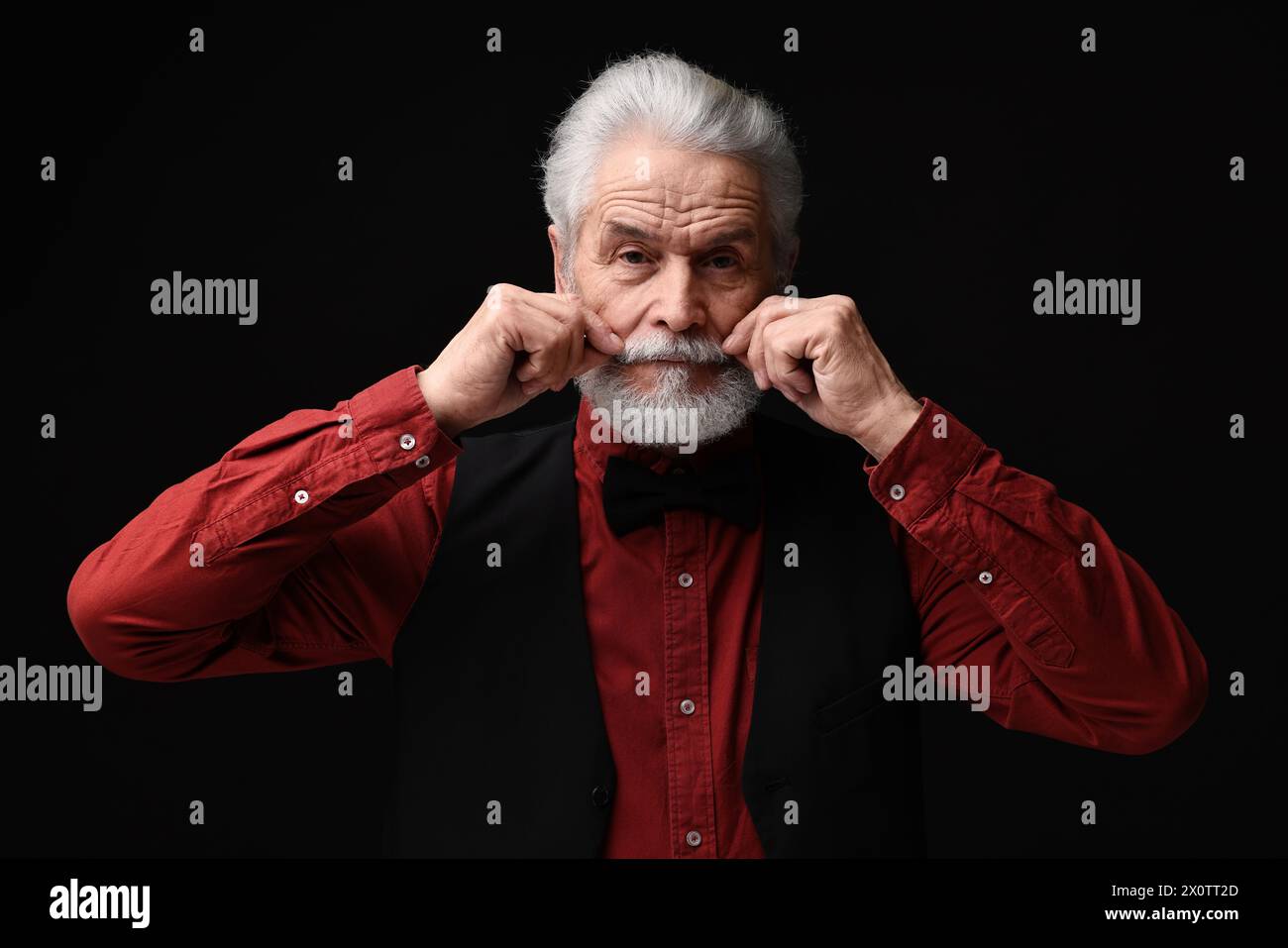 Senior man touching mustache on black background Stock Photo - Alamy