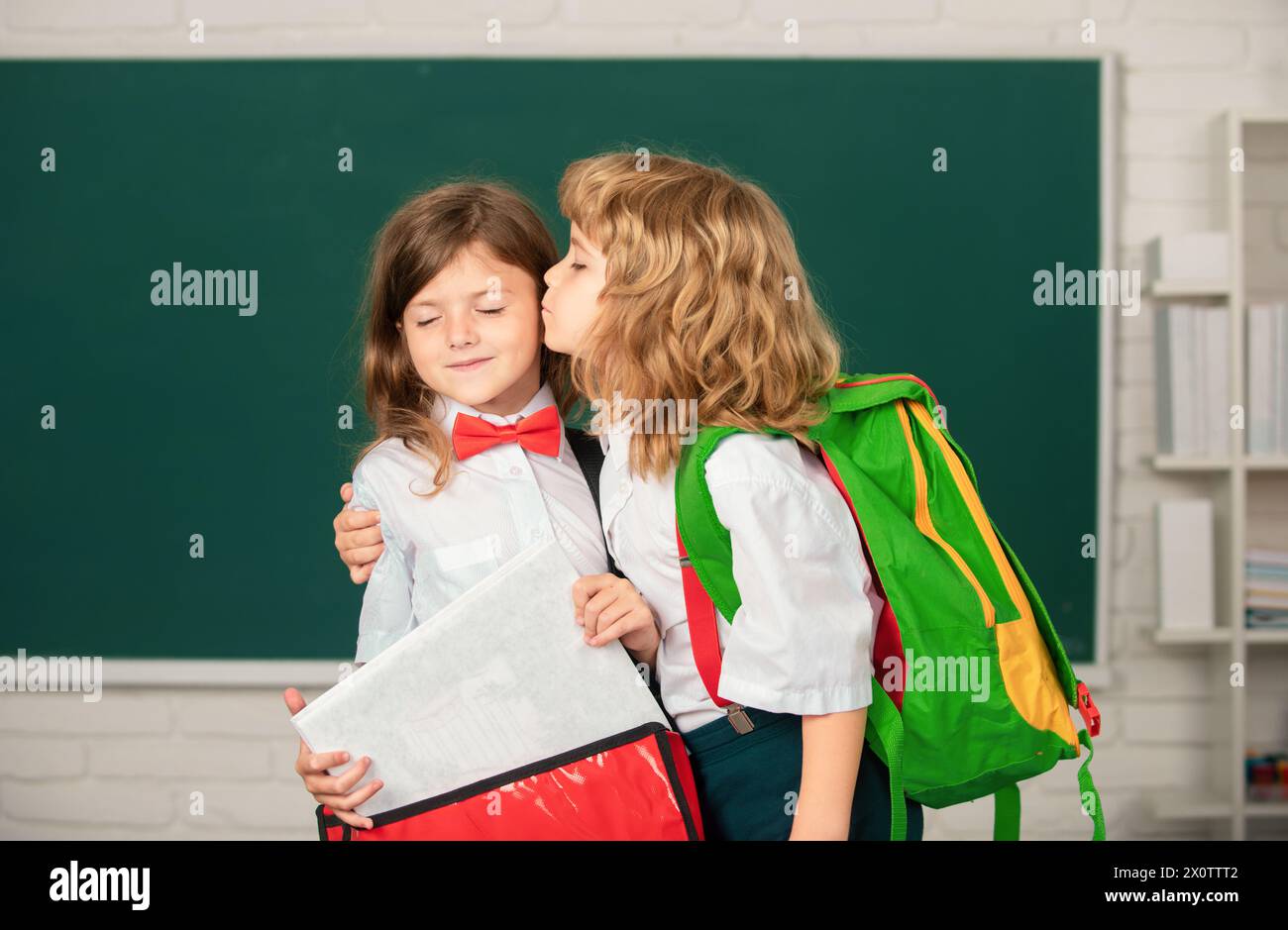 School friends, hug and kiss. Portrait of two happy school kids ...