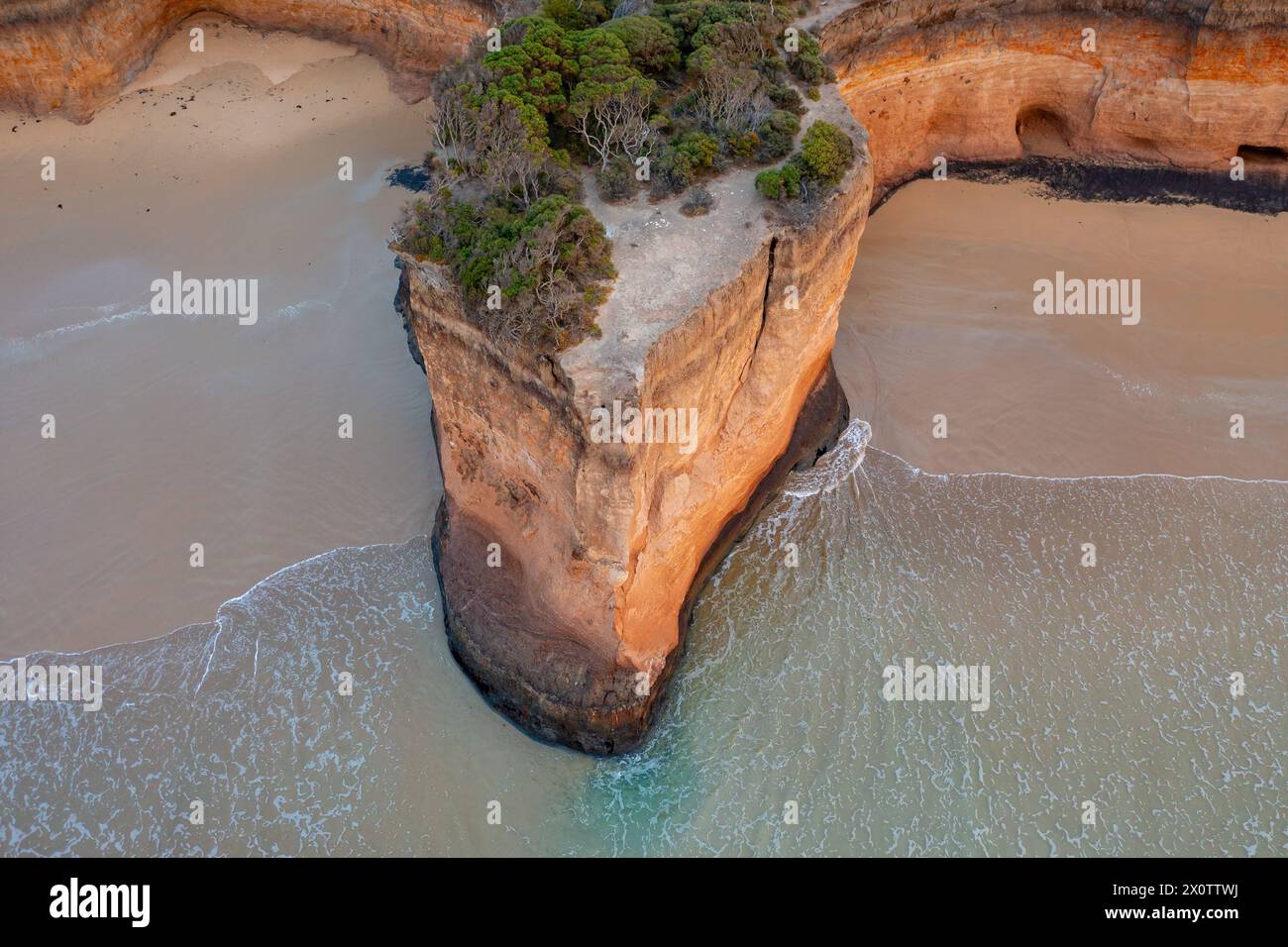 Aerial view of coastal cliff protruding out over a sandy beach at ...