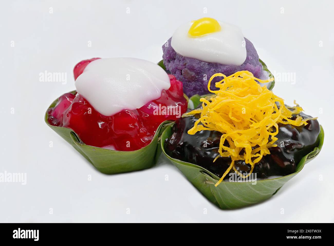 Close-up of 3 'upside-down' Khanom Tako Thai desserts, with a variety of toppings- purple taro ...