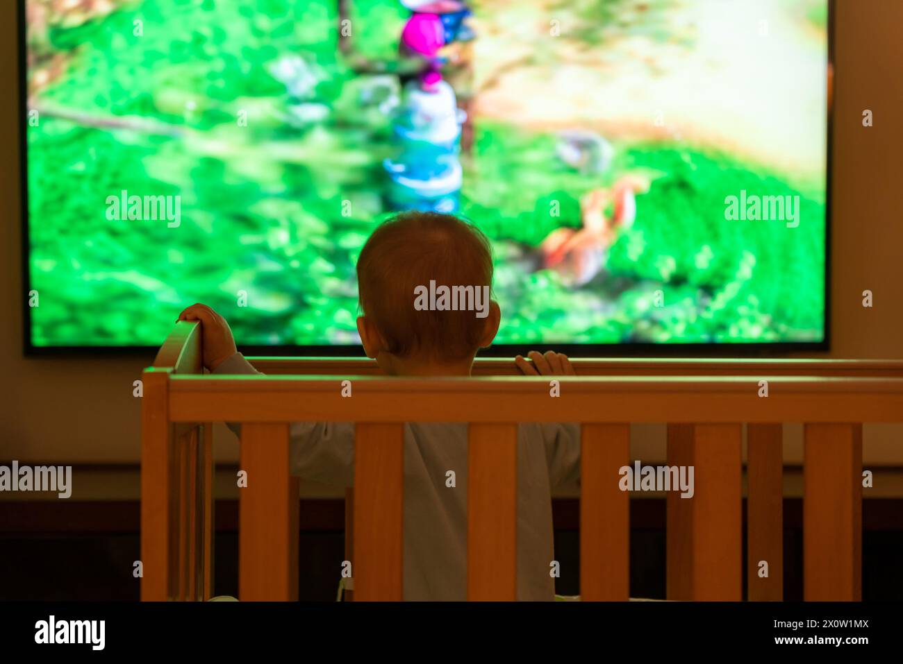 The baby watches a large TV from a crib. Concept of knowledge Stock ...