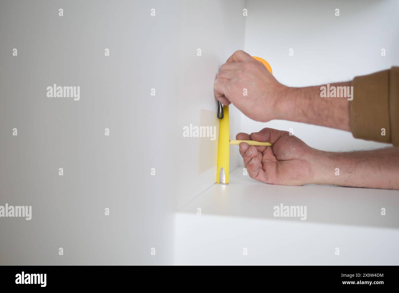 Man measuring wall with a tape measure Stock Photo - Alamy
