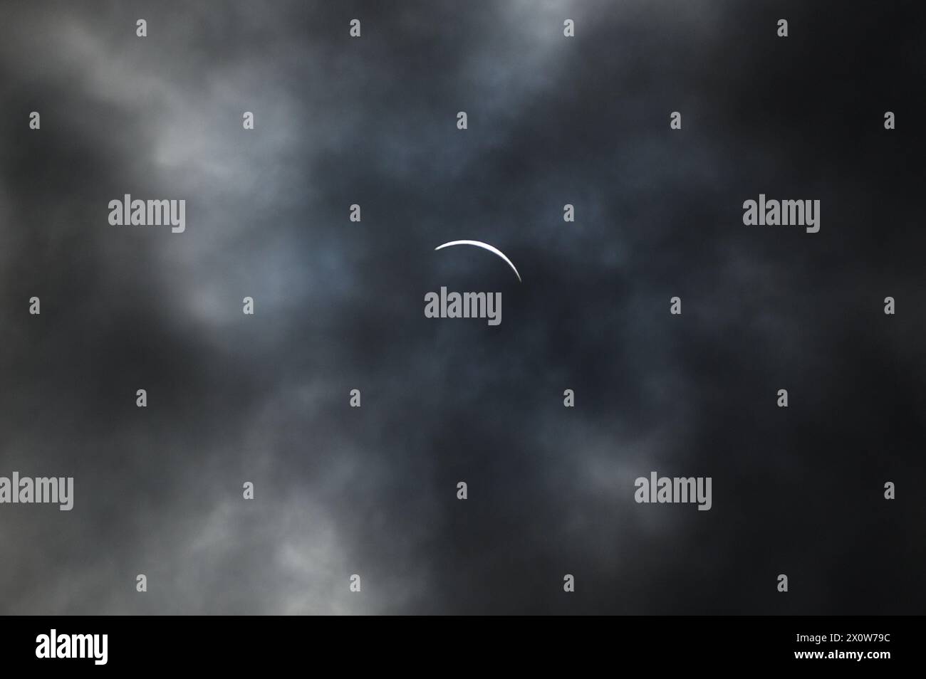 Toronto, ON, Canada - April 8, 2024: Partial solar eclipse 2024 seen from a cloudy sky near ...