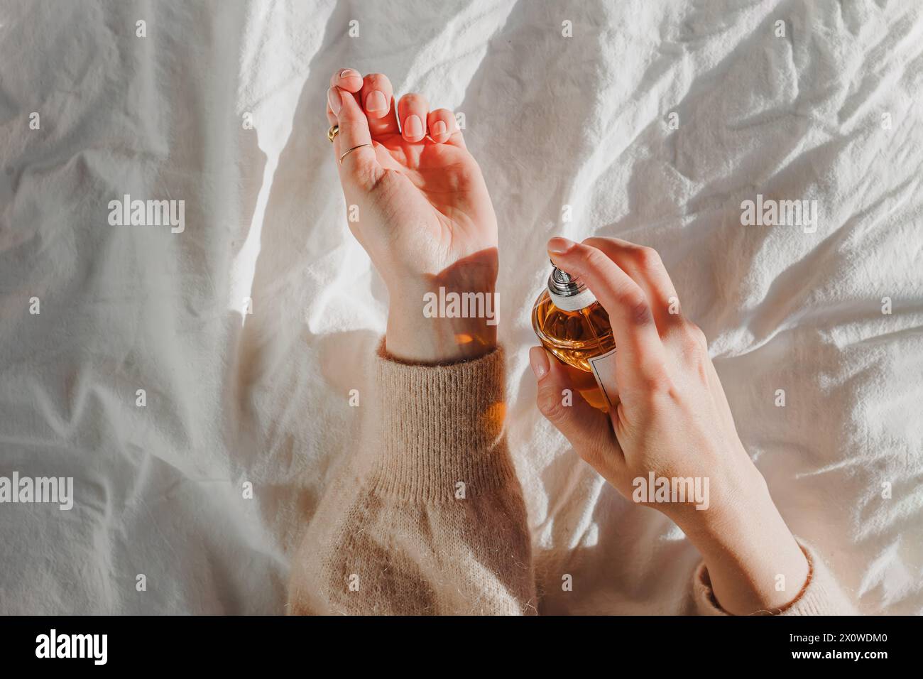 Female hands holding a bottle of perfume in natural morning light ...