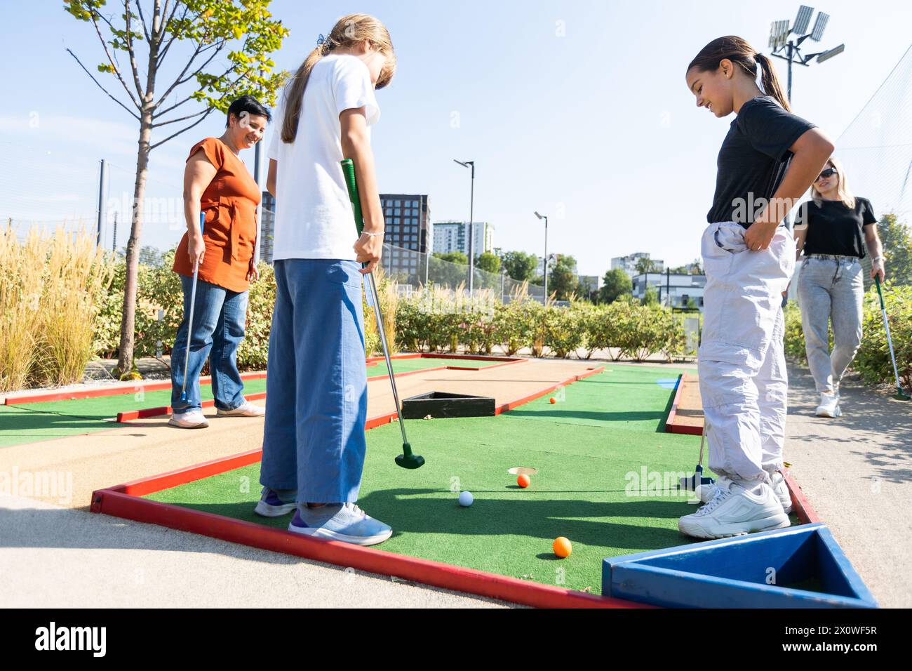 Cute school girl playing mini golf with family. Happy toddler child ...