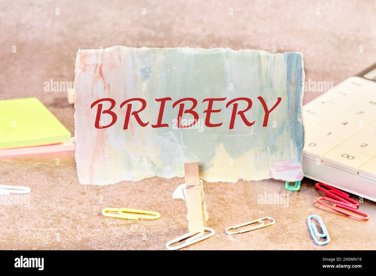 Word BRIBERY written on a colored piece of paper in a clothespin Stock ...
