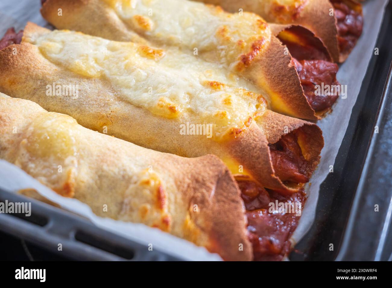 Cooked and ready to eat homemade mexican enchiladas on baking oven tray ...