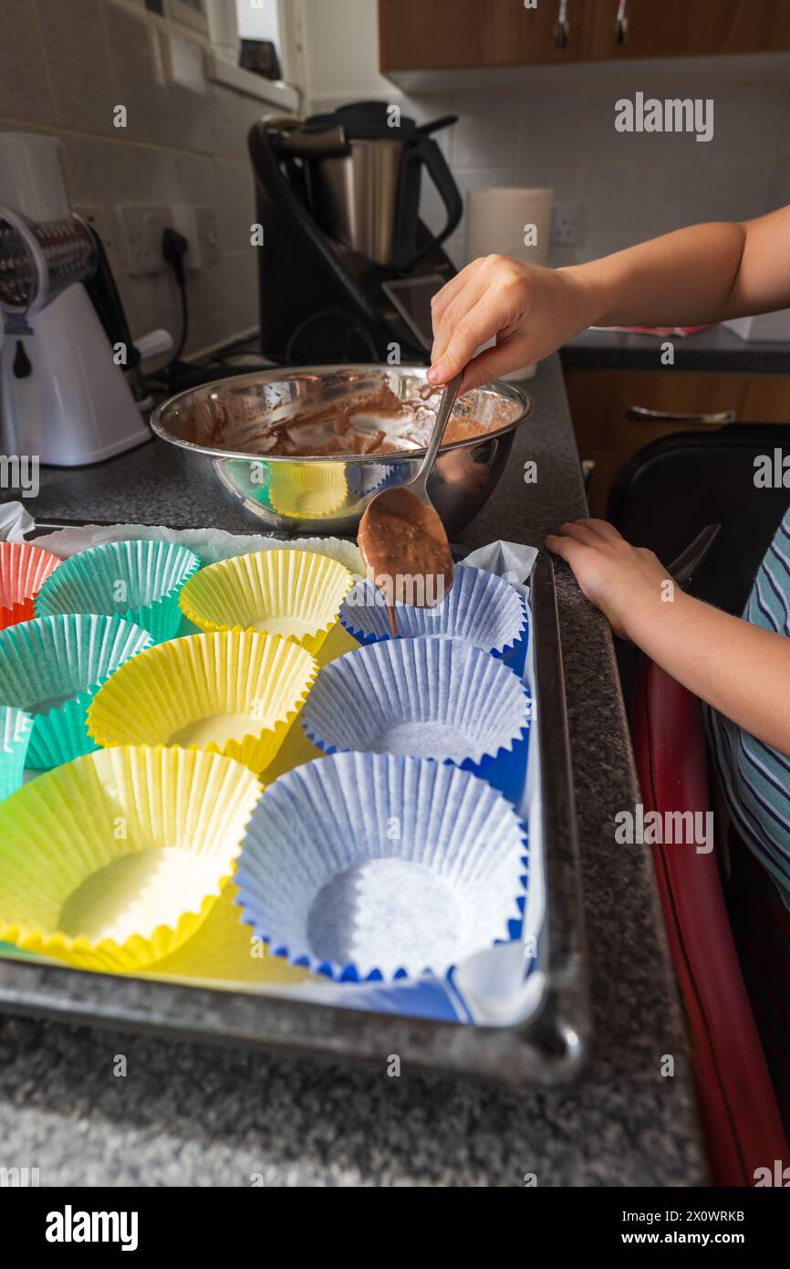 Child hands adding cupcake mix into colorful baking liners Stock Photo ...