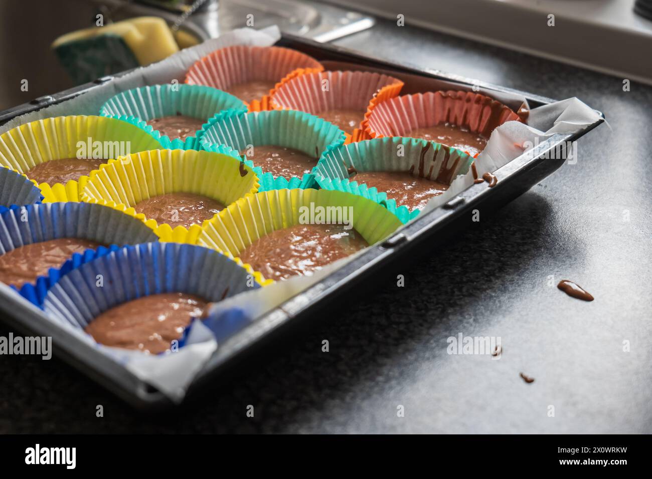 Chocolate cupcake mix sitting inside colorful baking liners inside ...