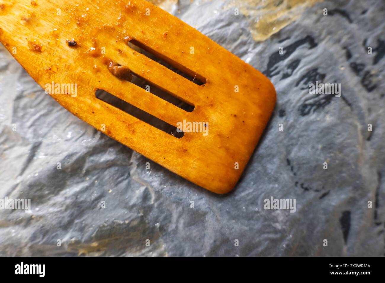 Used dirty wooden mixing spoon inside empty tray lined with baking ...