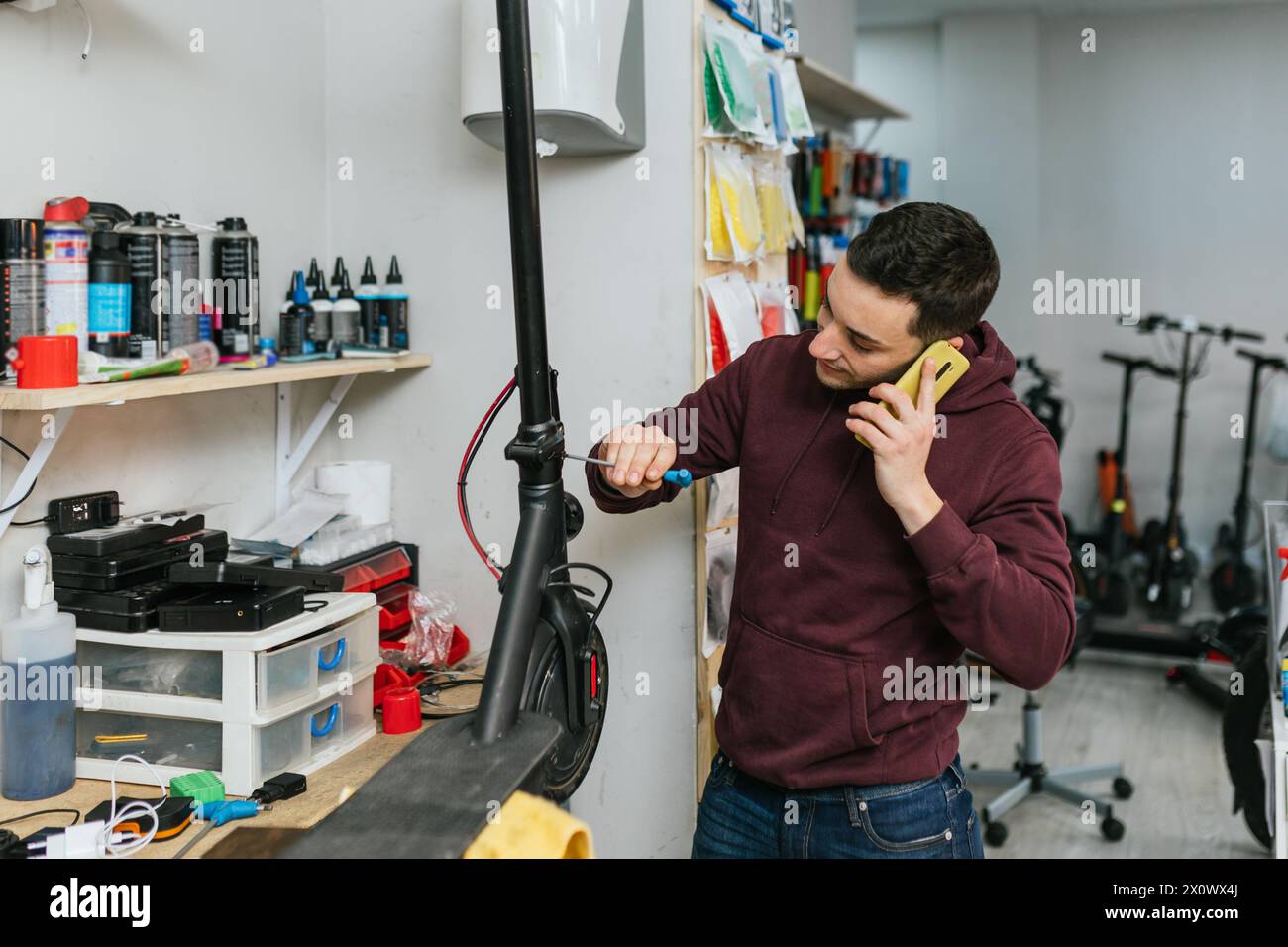 The bike mechanic attends a call while repairing an electric scooter ...