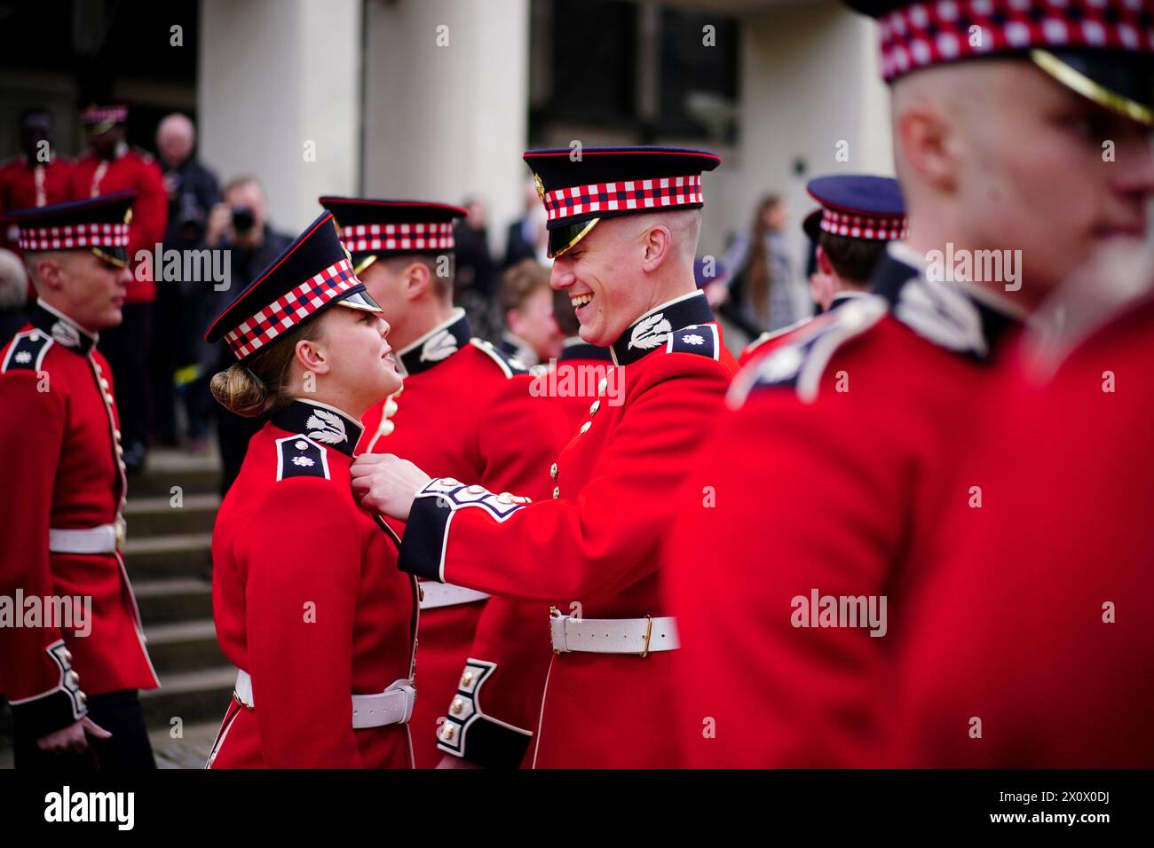 A members of the Scots Guards helps a colleague with her uniform ahead ...