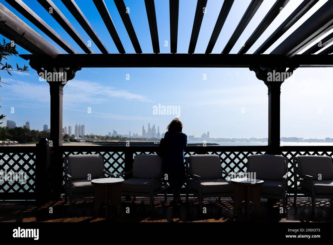 Single female looking out from under pergola towards The Palm, Dubai ...