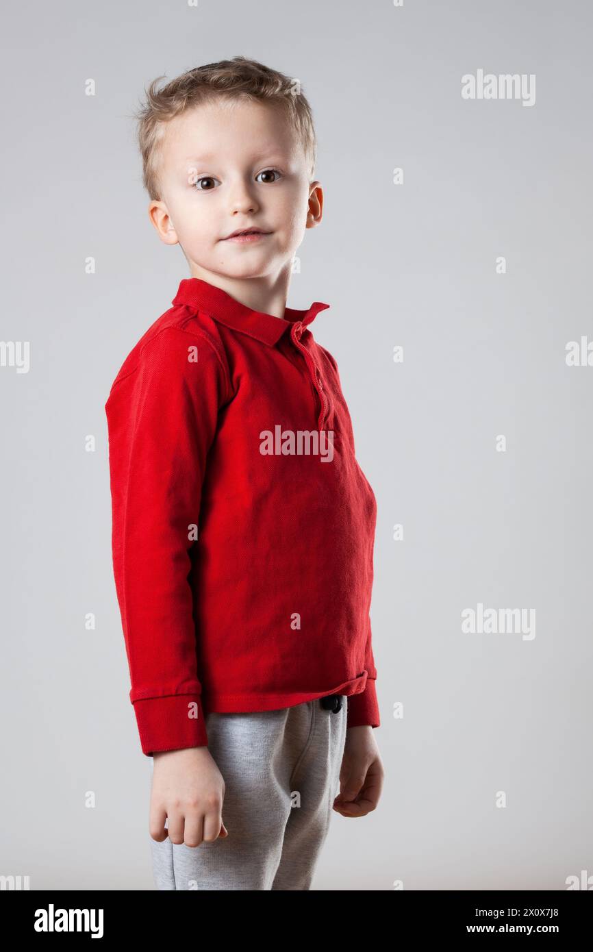 Portrait of a happy little boy in red blouse standing upright and ...