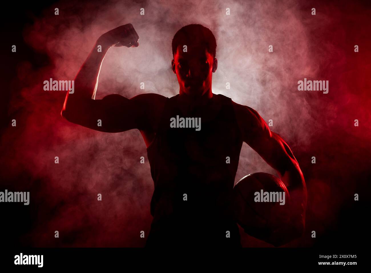 Silhouette basketball player side lit with red color holding a ball ...