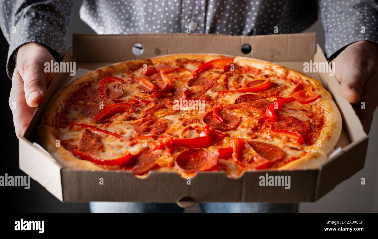Caucasian male hands hold large open carton box with pepperoni pizza ...