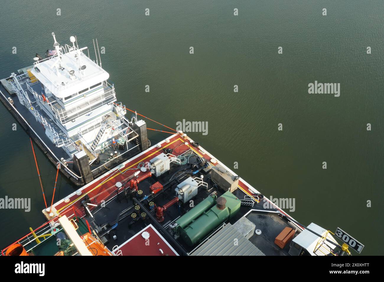Tug boat with white superstructure and bunker barge with valves and ...