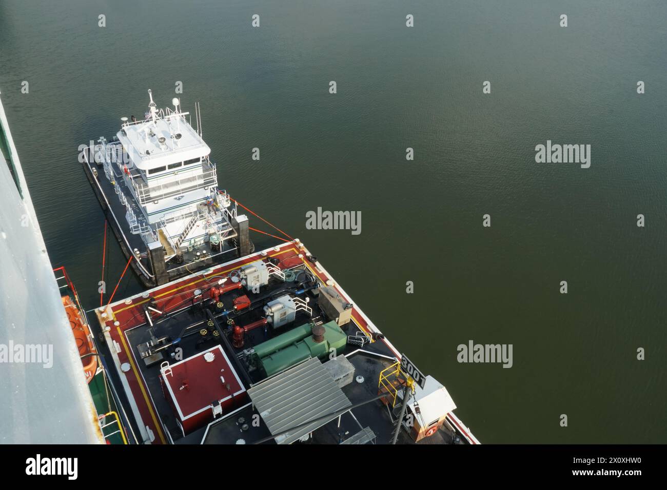 A tugboat featuring a white superstructure and a bunker barge equipped ...