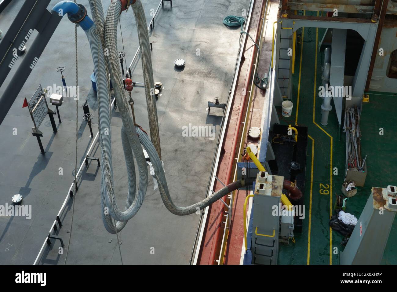Fuel hose of bunker barge attached to crane and connected to container ...