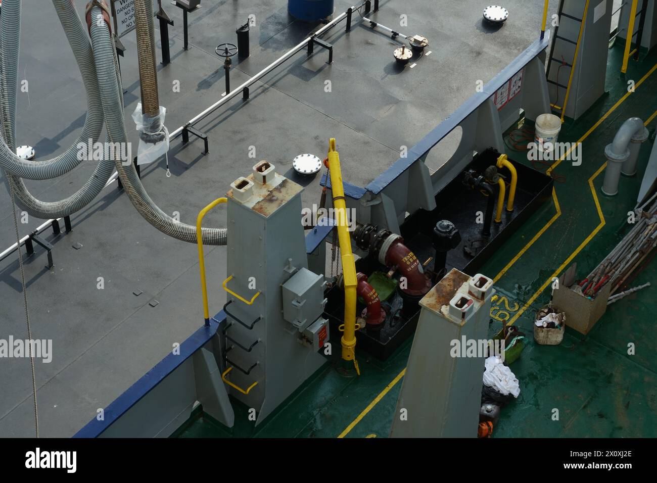 Close view on fuel hose of bunker barge on crane connected to container ...